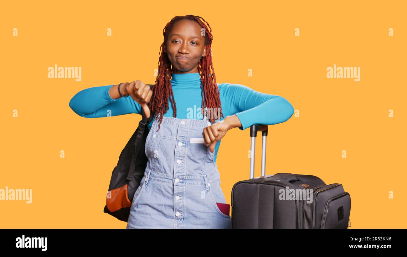 Young adult giving thumbs down sign in studio, showing disapproval ...