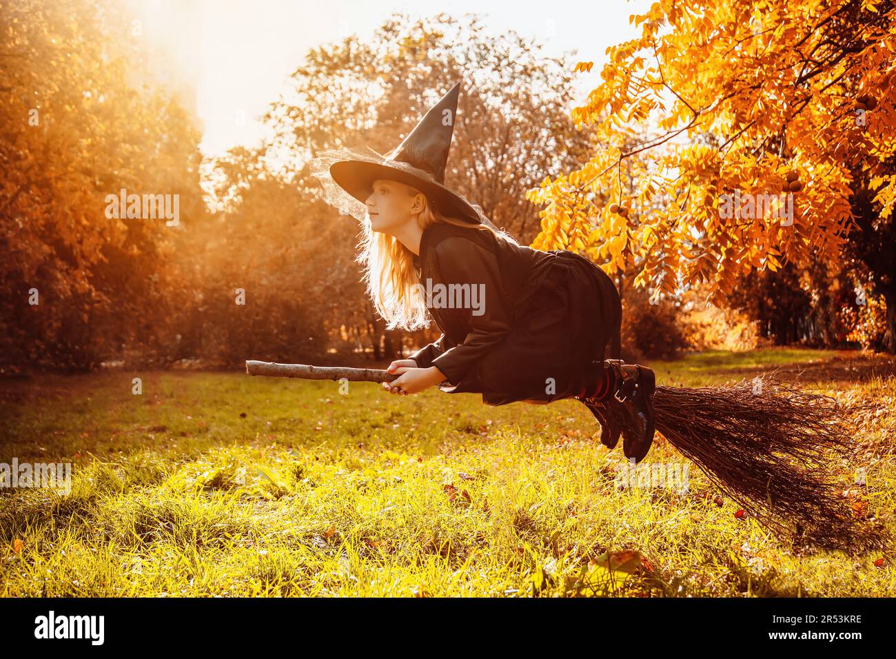 A girl in a witch costume sits on a floating broom Stock Photo - Alamy