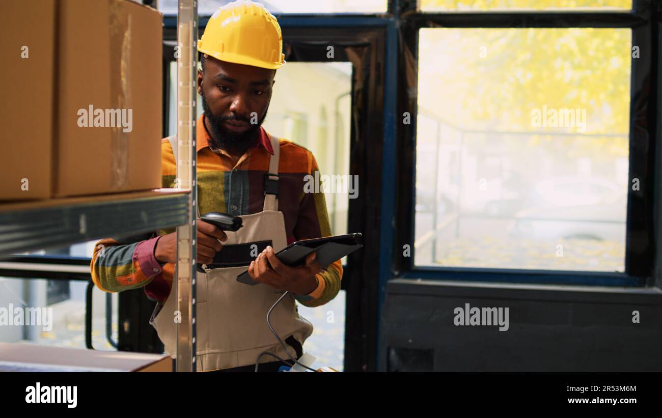 Young employee scanning goods on racks in storage room, working with ...