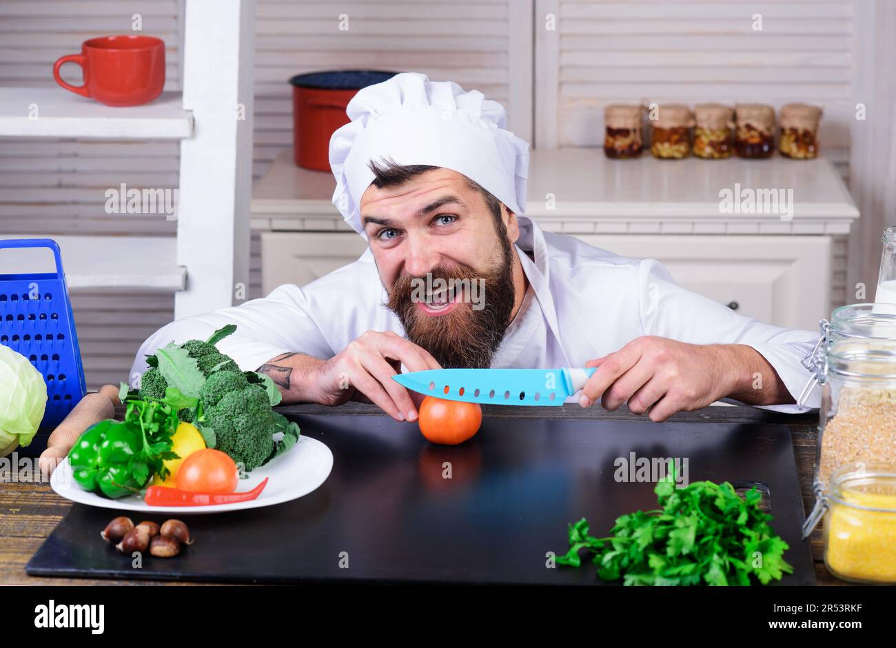Male chef preparing tasty fresh vegetable salad. Chef with sharp knife ...