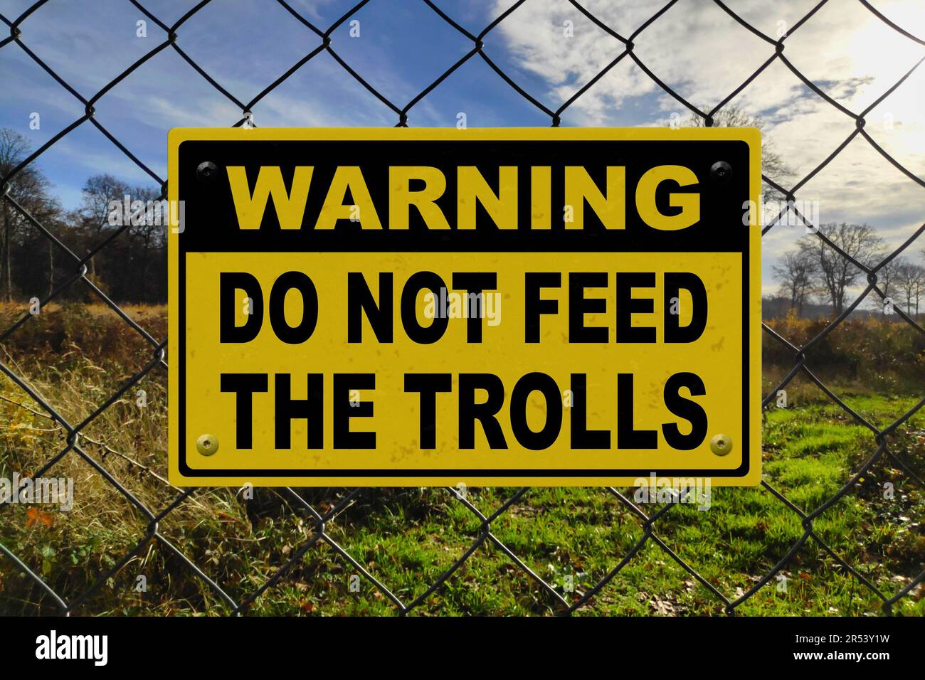 Black and yellow warning sign on a fence stating in "Warning - Do not feed the trolls Stock ...