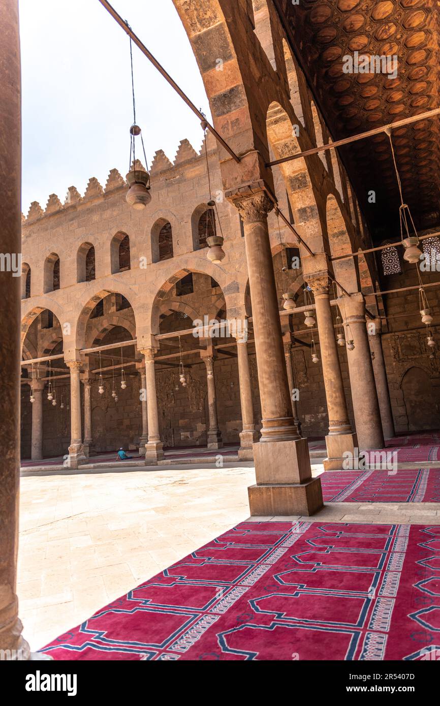 Tall ceilings and arches of an old mosque in Cairo with red carpets ...