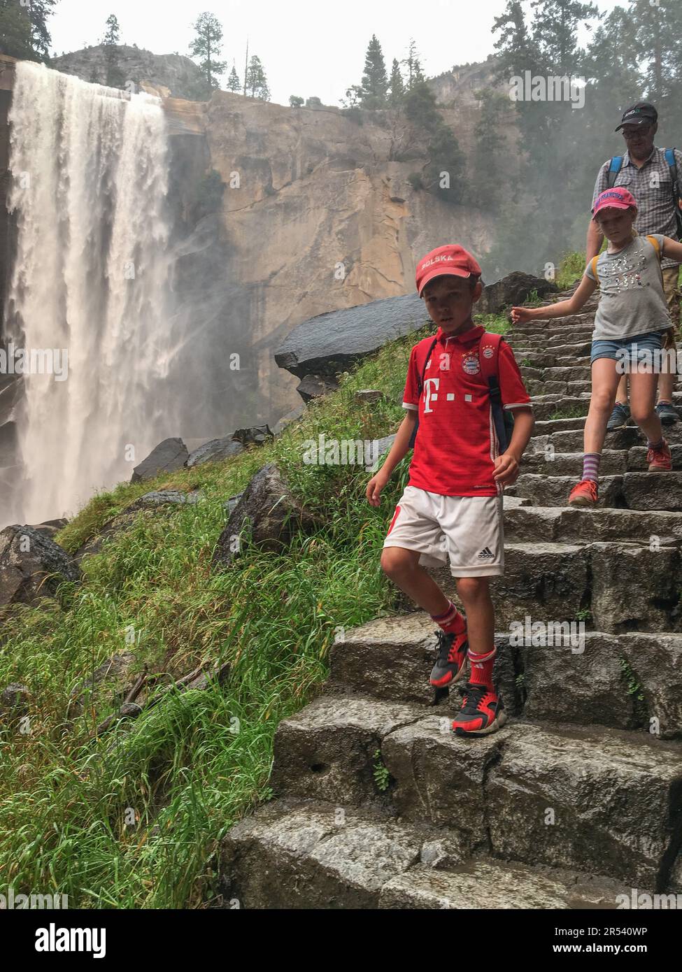 A father and his son and daughter children hike down the stone steps of ...