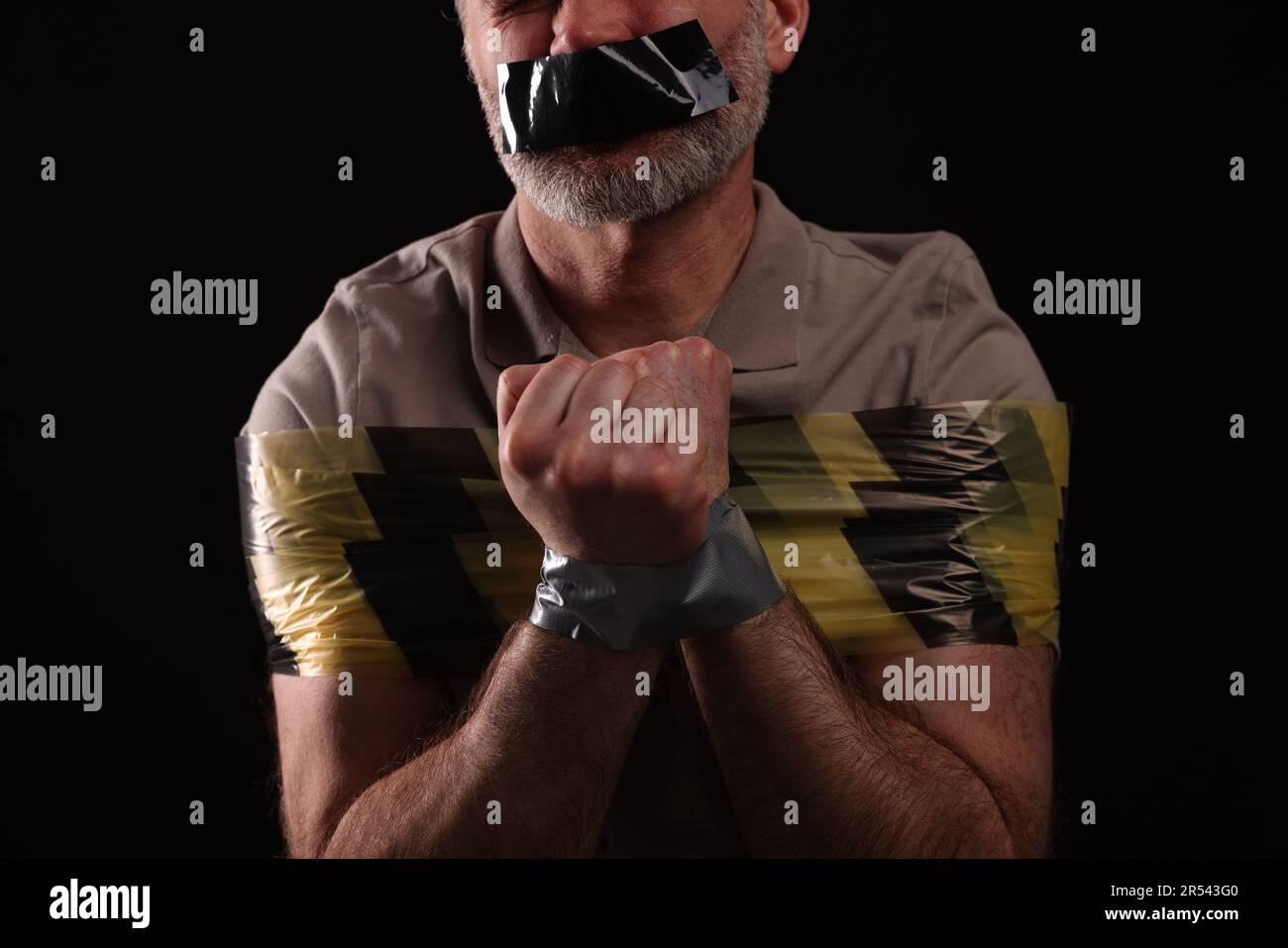 Victim tied with duct tape on black background, closeup. Hostage taking ...