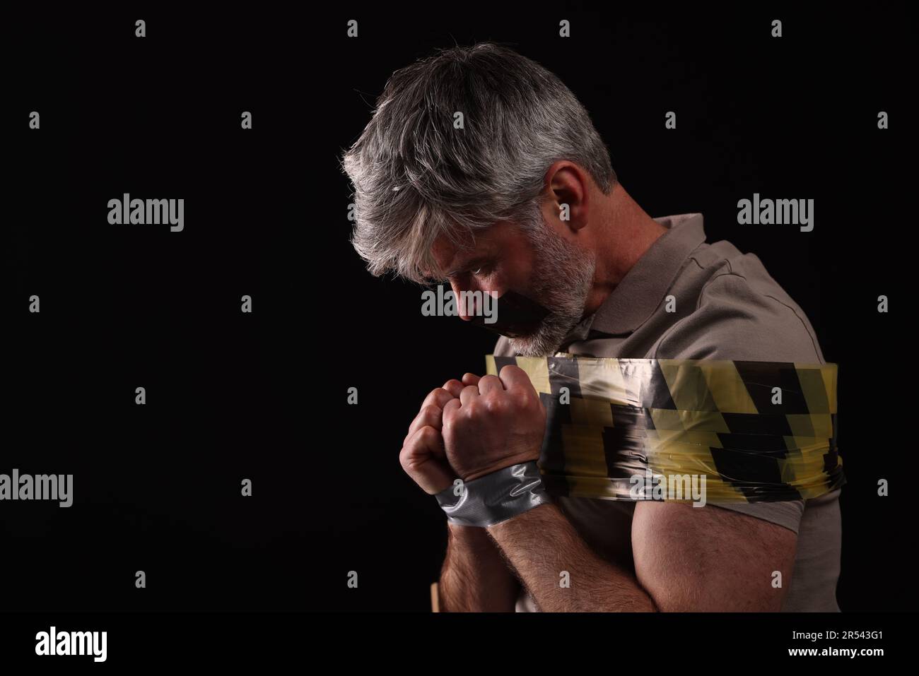 Victim tied with duct tape on black background, space for text. Hostage ...