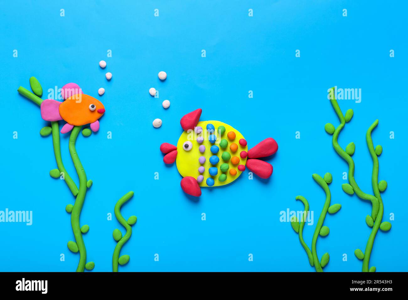 Seaweed and fish made of plasticine on light blue background, flat lay ...