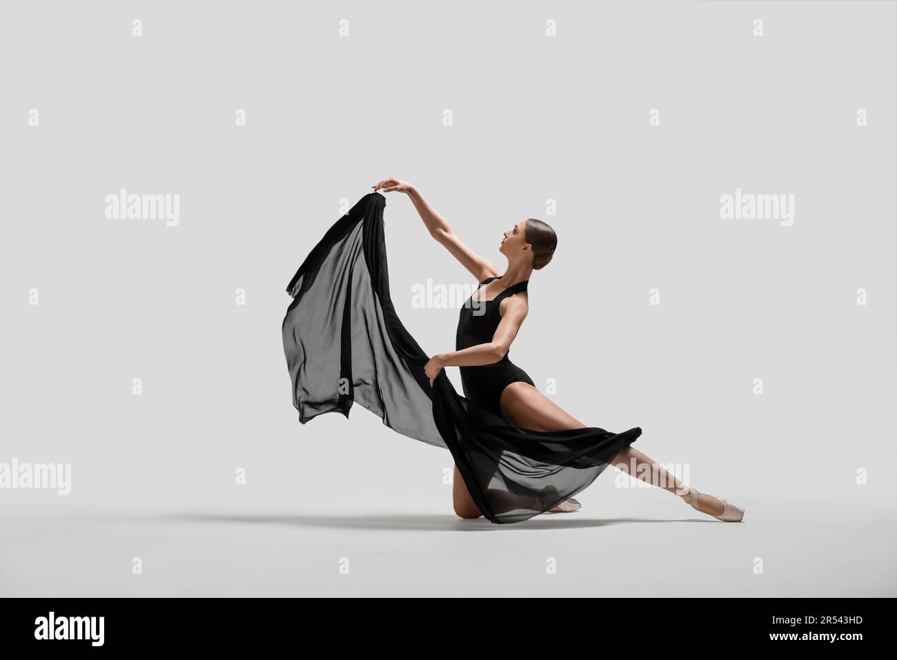 Graceful young ballerina practicing dance moves with black veil on ...