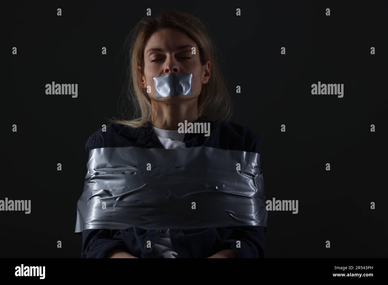 Woman taped up and taken hostage on dark background Stock Photo - Alamy