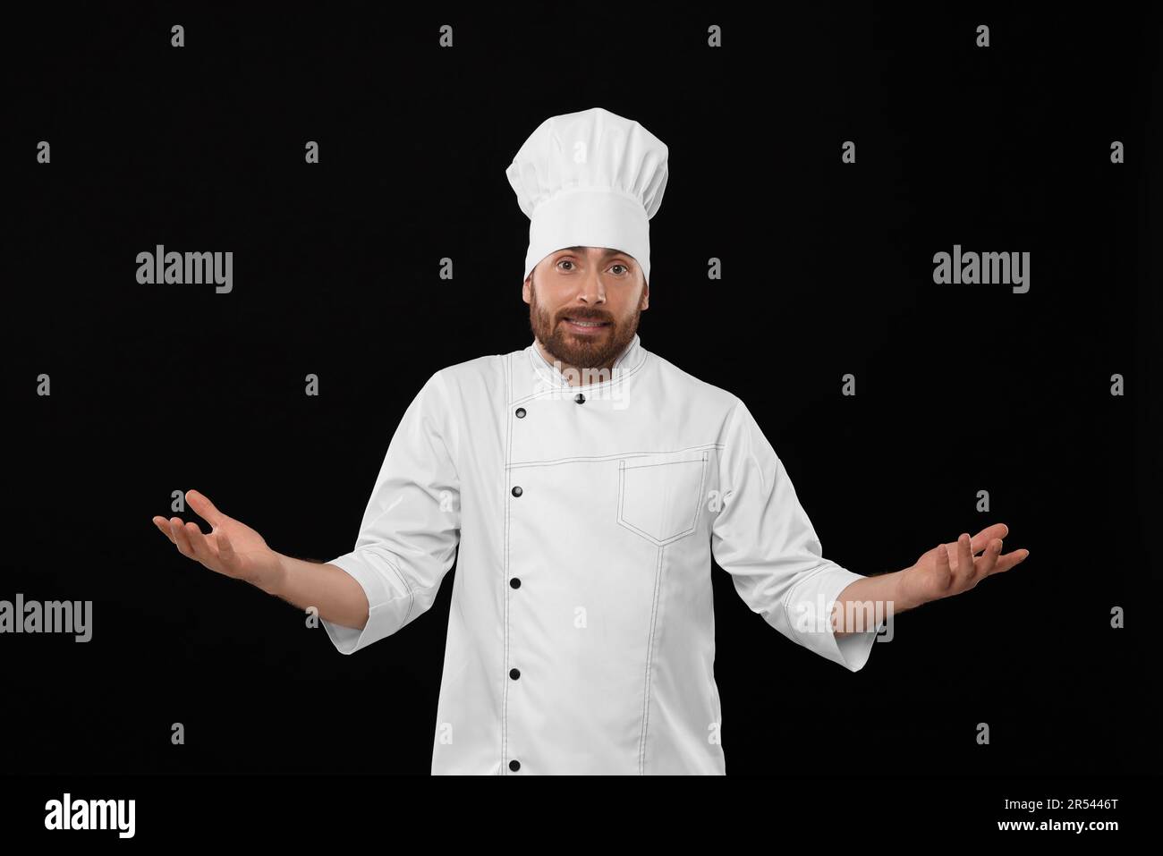 Puzzled mature male chef on black background Stock Photo - Alamy