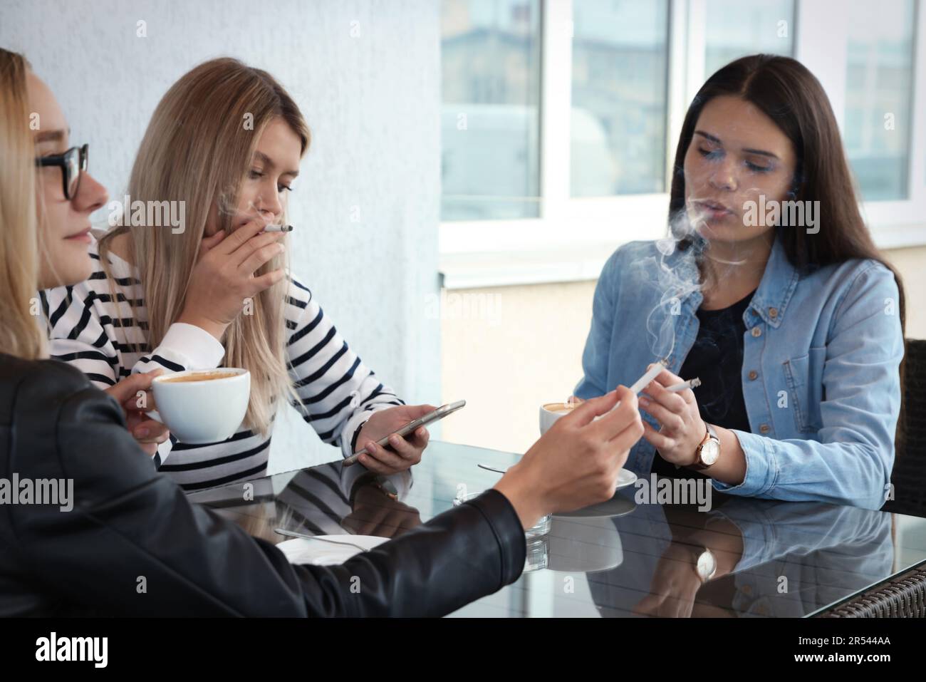 Women smoking cigarette at table in outdoor cafe Stock Photo - Alamy