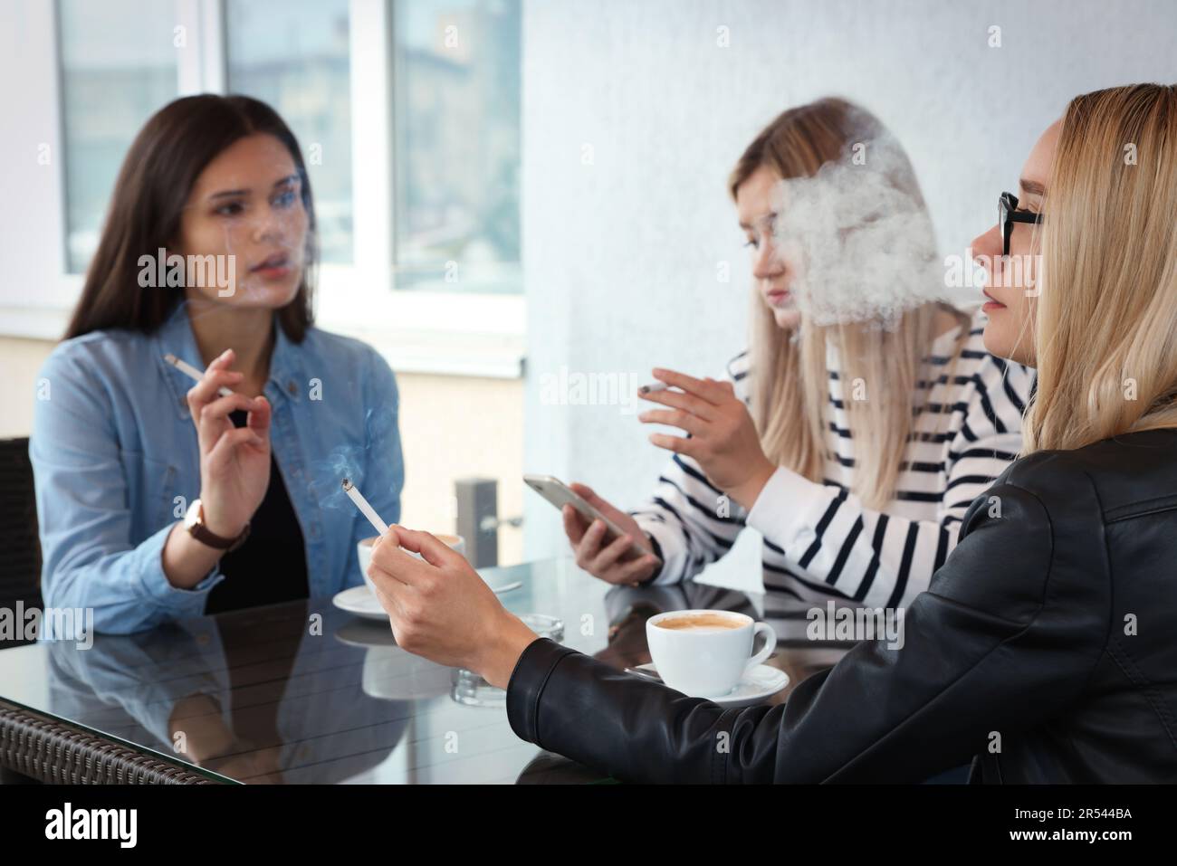 Women smoking cigarette at table in outdoor cafe Stock Photo - Alamy