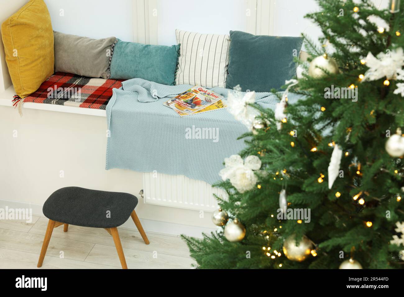 Beautiful Christmas tree near cozy window sill with pillows in room ...
