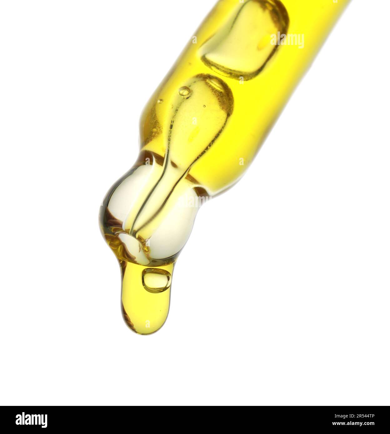 Dripping yellow facial serum from pipette on white background, closeup ...