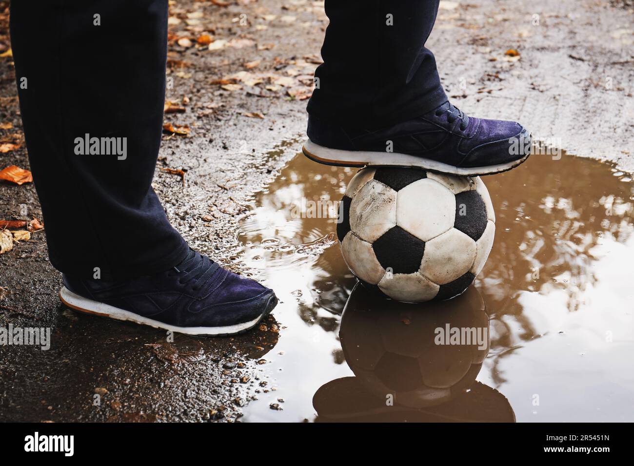 Man with soccer ball in muddy puddle outdoors, closeup Stock Photo - Alamy