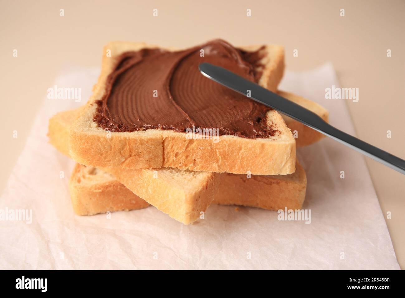 Tasty toast with chocolate paste and knife on light background Stock ...