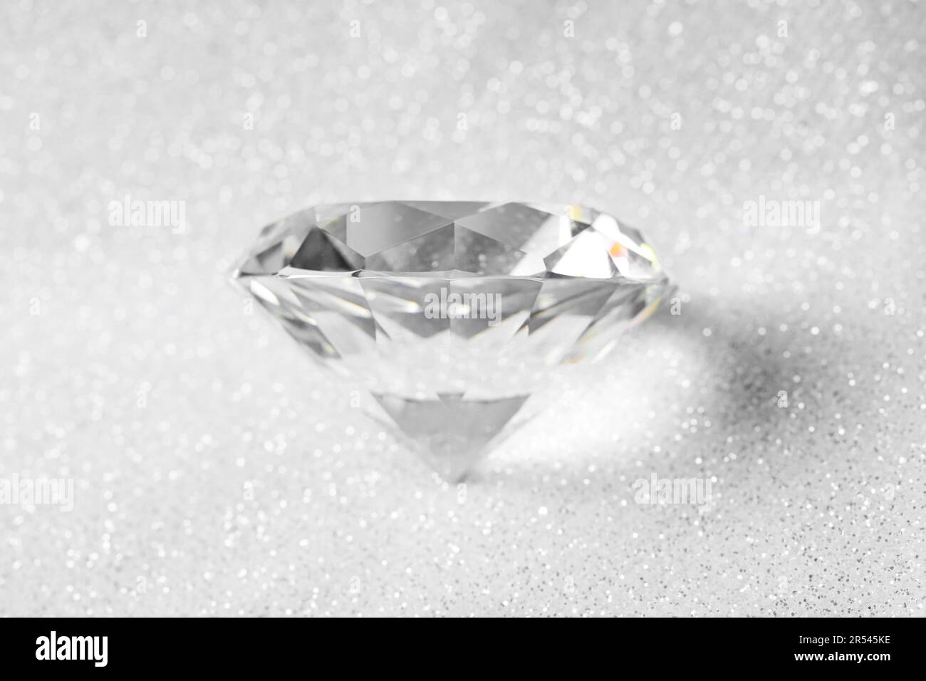 Beautiful dazzling diamond on shiny glitter background, closeup ...