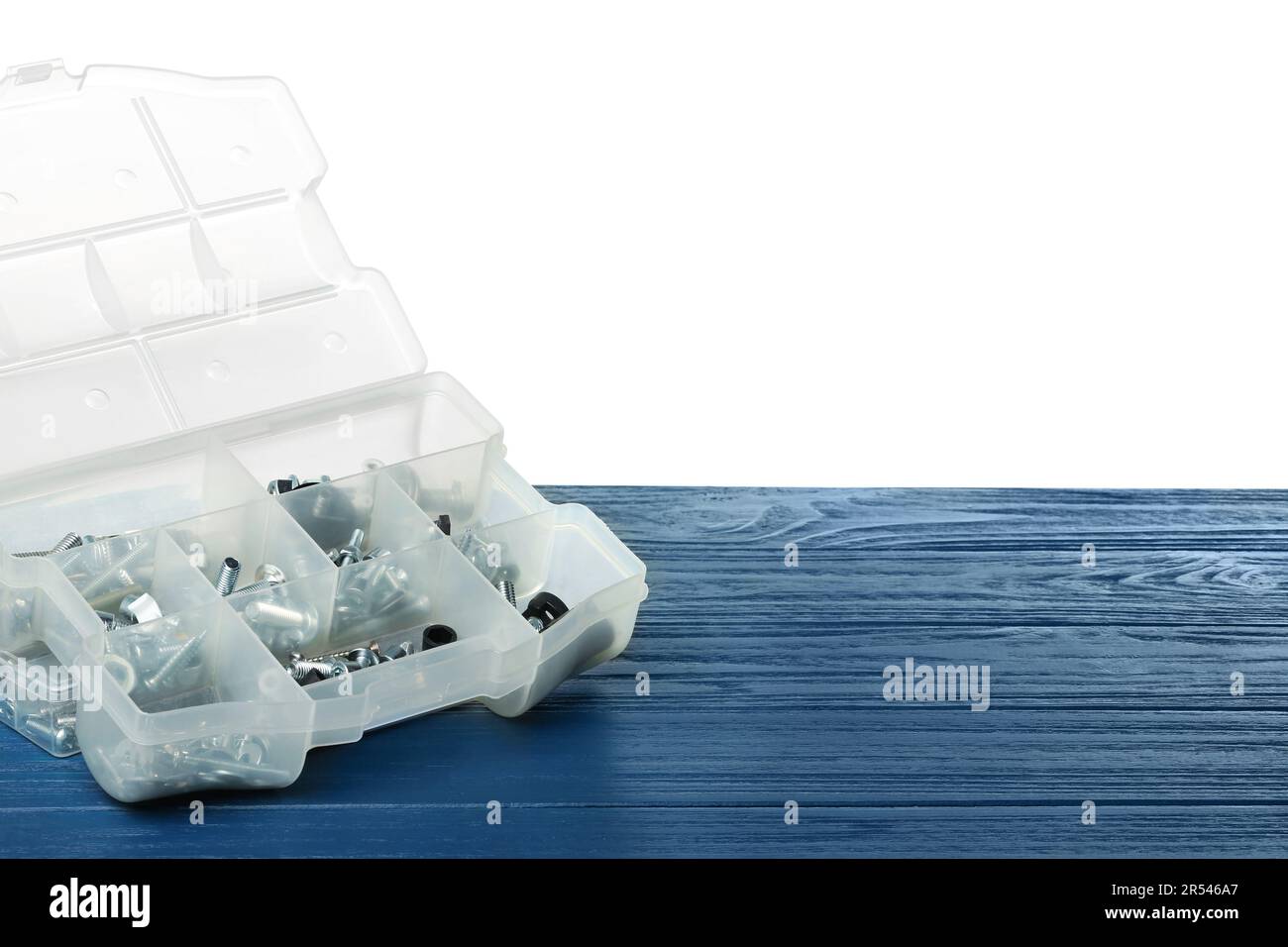 Plastic box with different bolts and nuts on grey wooden table against ...