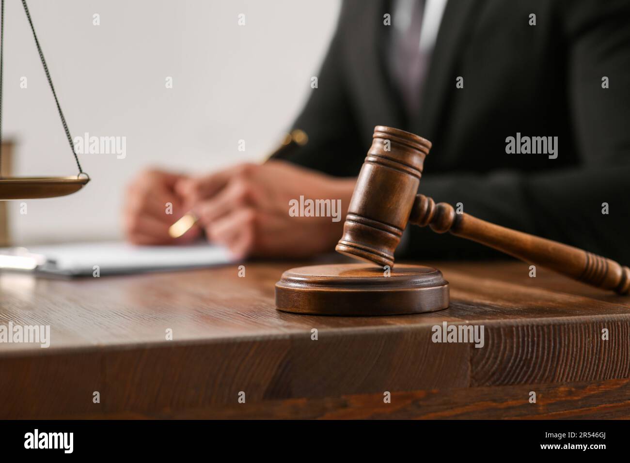 Law and justice. Closeup of judge working at wooden table, focus on ...