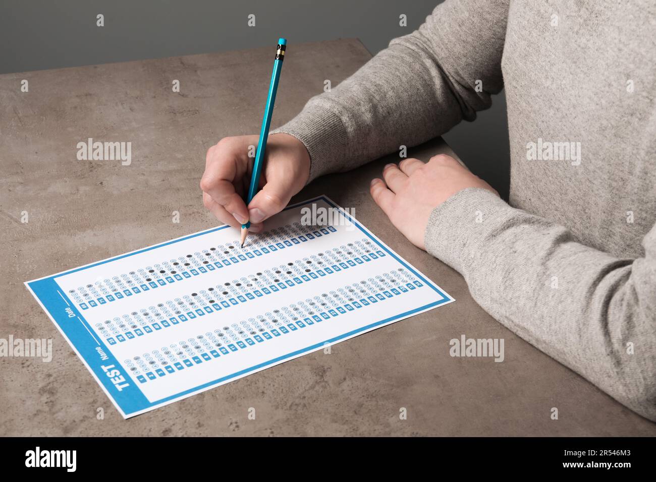 Student filling answer sheet at grey table, closeup. Passing exam Stock ...