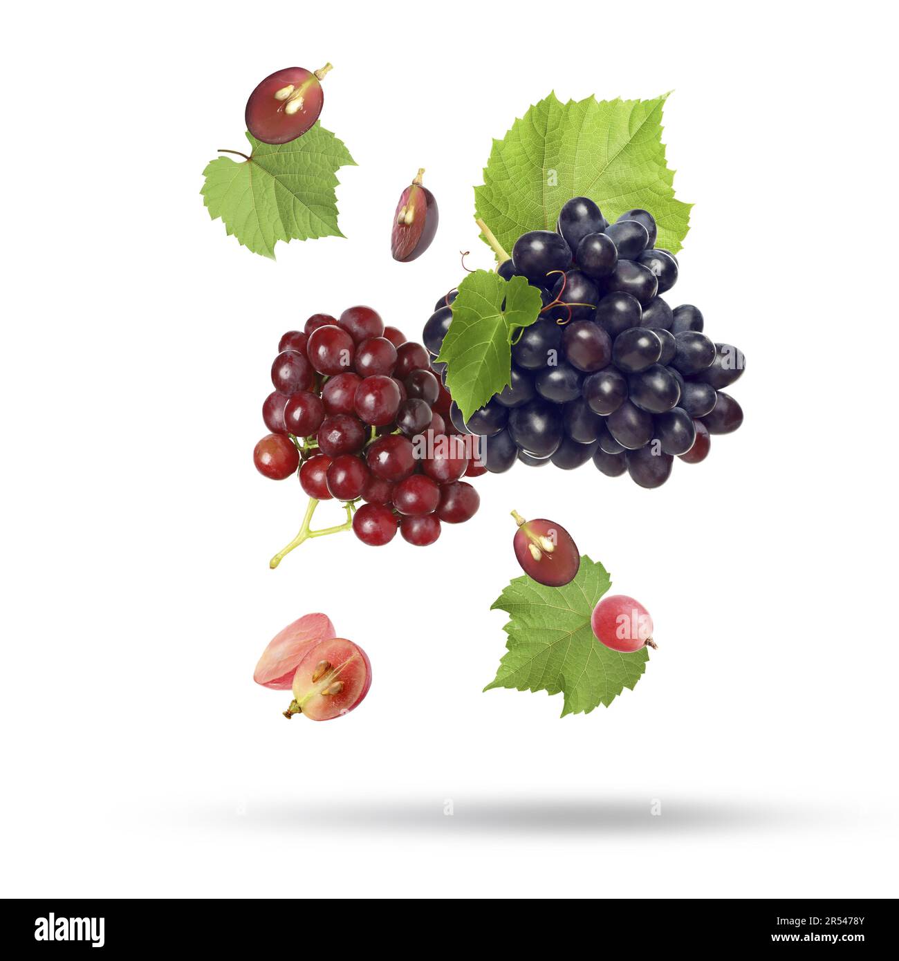 Different fresh ripe grapes and green leaves falling on white ...