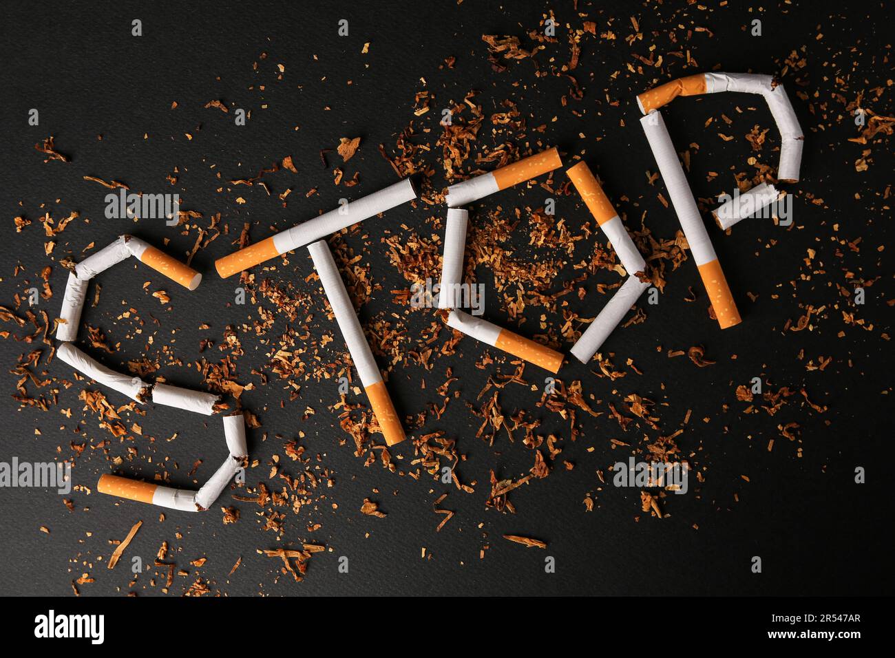 Word Stop made of broken cigarettes on black background, flat lay ...