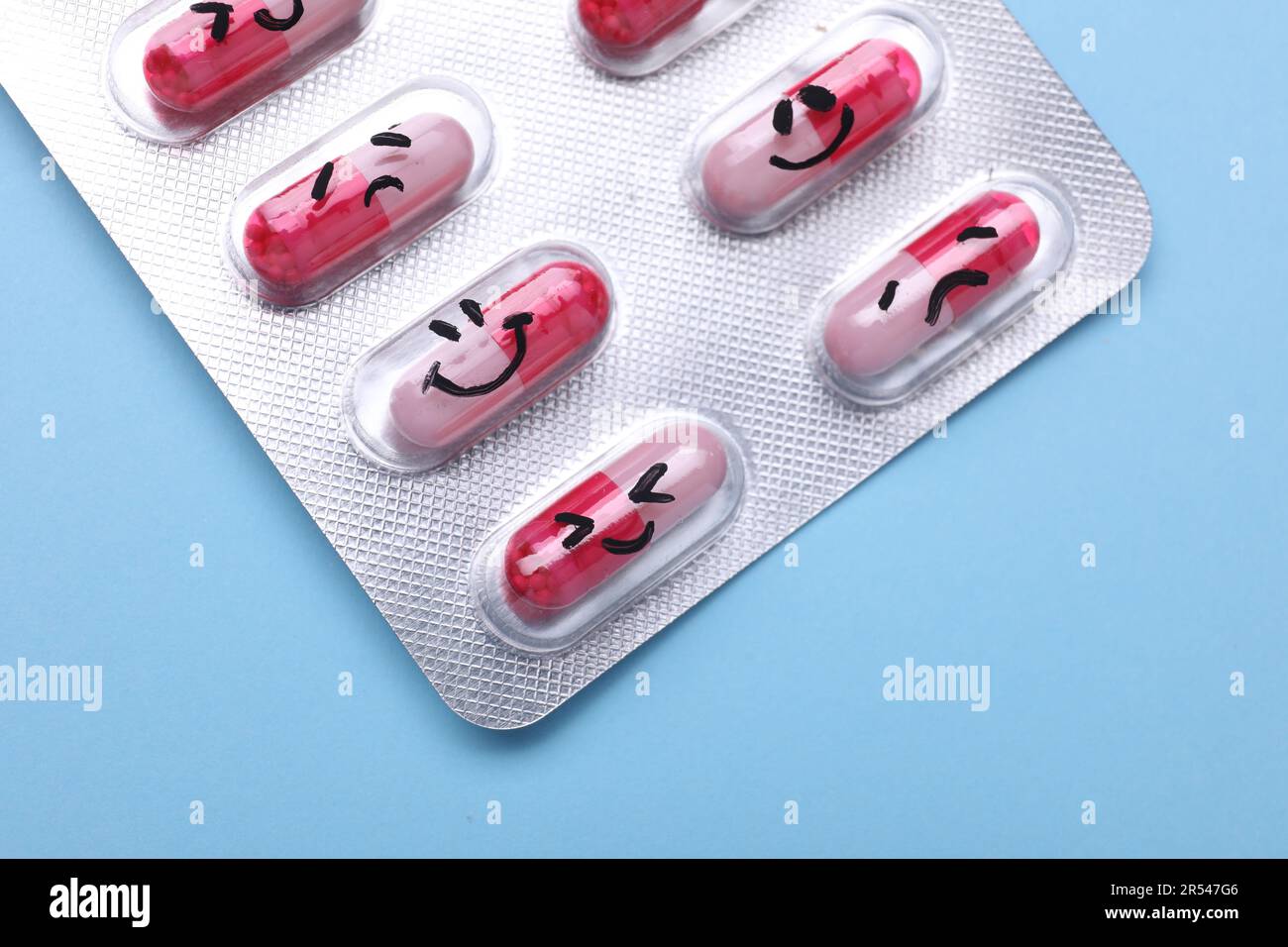 Blister of antidepressant pills with emotional faces on light blue ...