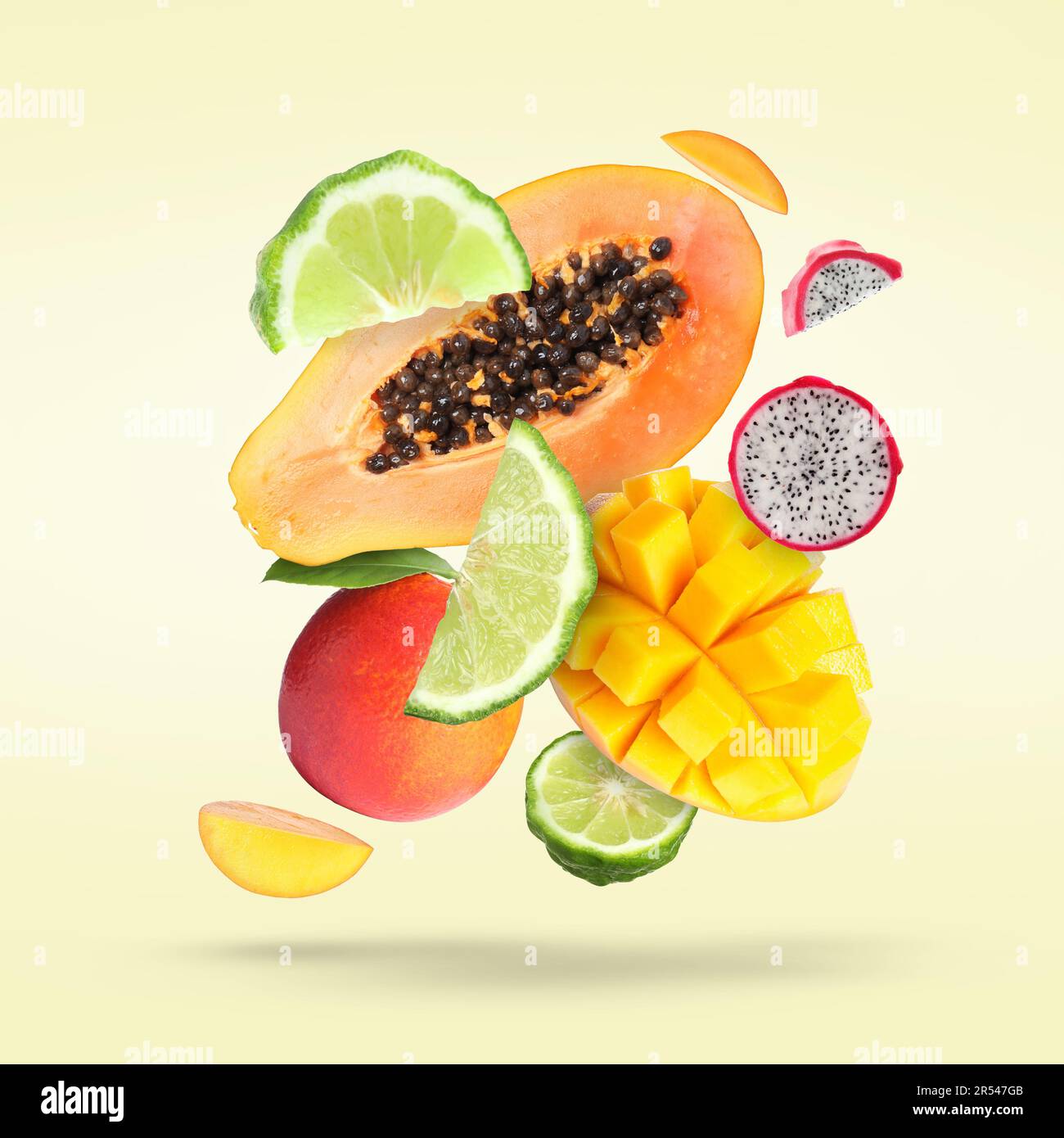 Many fresh tropical fruits falling on light pale yellow background ...