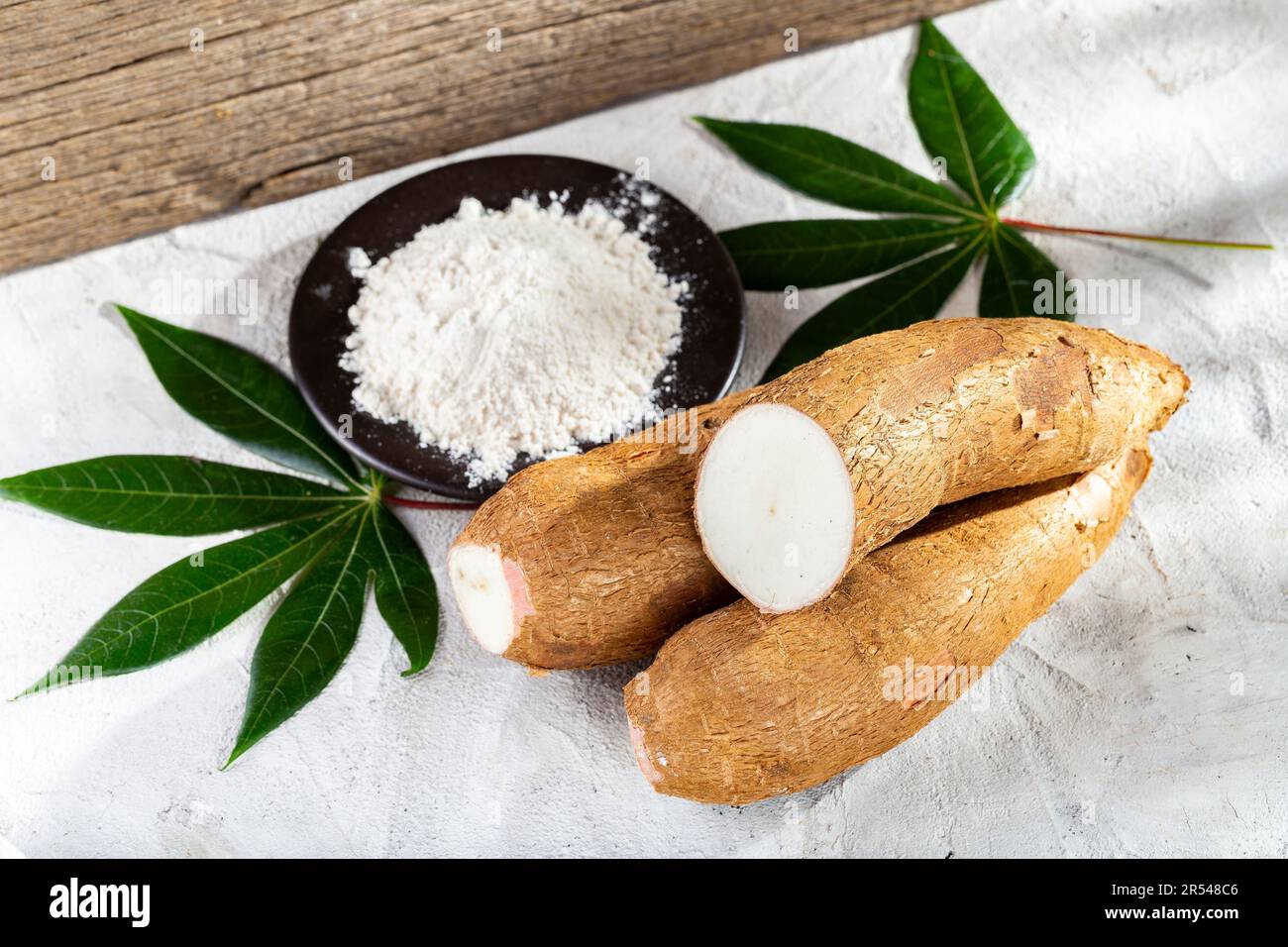 pile of cassava root and cassava flour on a gray and white textured ...