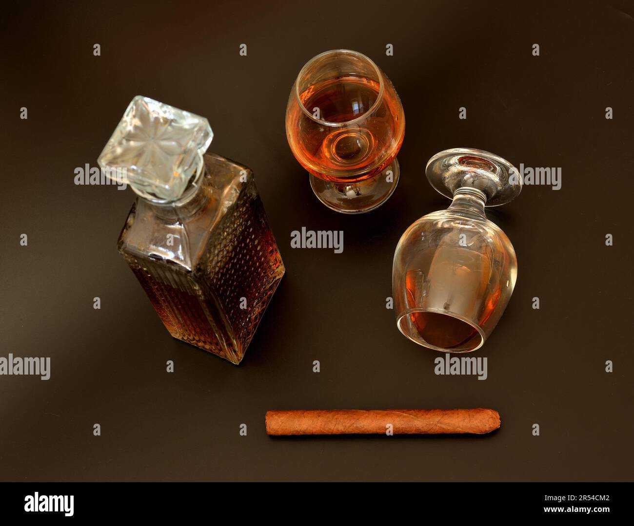 Two glass goblets, a crystal decanter of cognac and a Cuban cigar on a ...