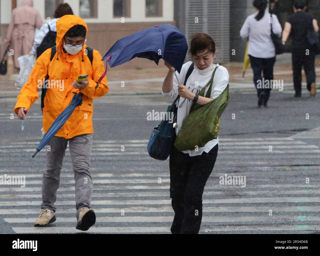 People walk on a street while tilting umbrellas in Naha City, Okinawa ...
