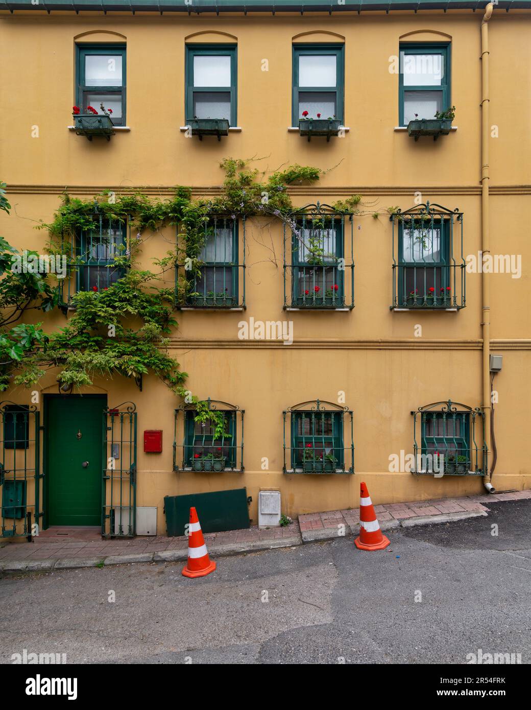 Facade of residential building with walls painted in orange and green, with wrought iron window ...