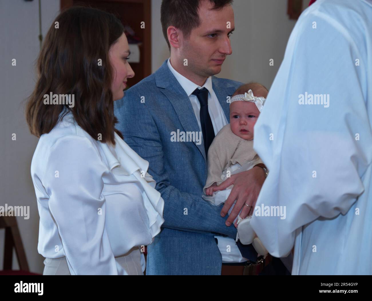 Parents holding their baby girl in a church ready for christening Stock Photo - Alamy