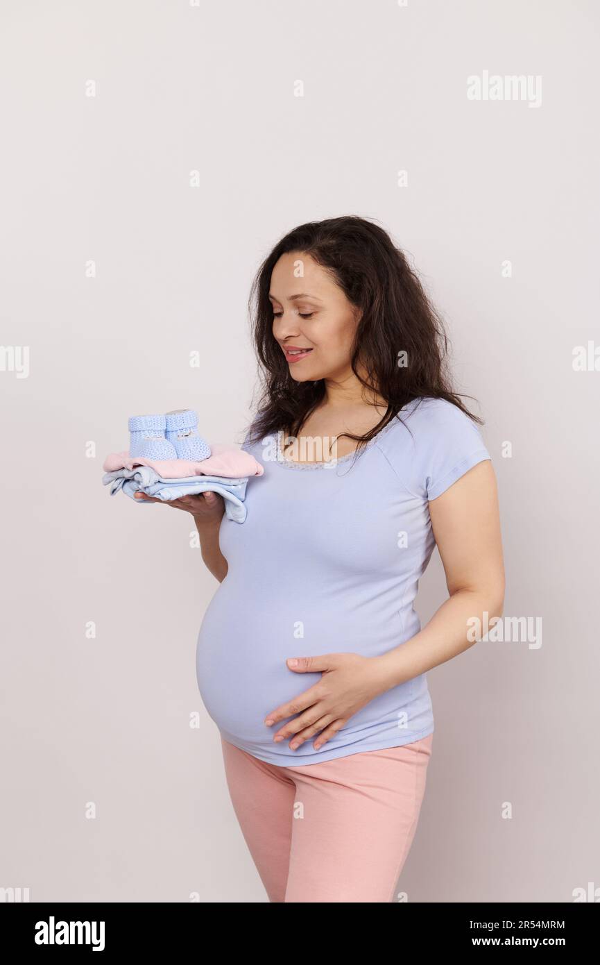 Happy pregnant future mother expecting baby, holds a pile of baby ...