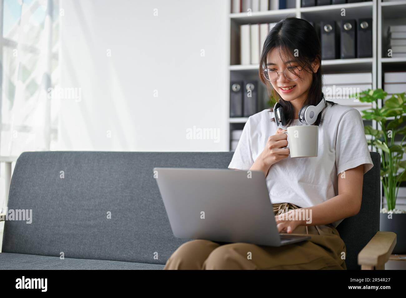 A charming young Asian female freelancer uses her laptop to manage her ...