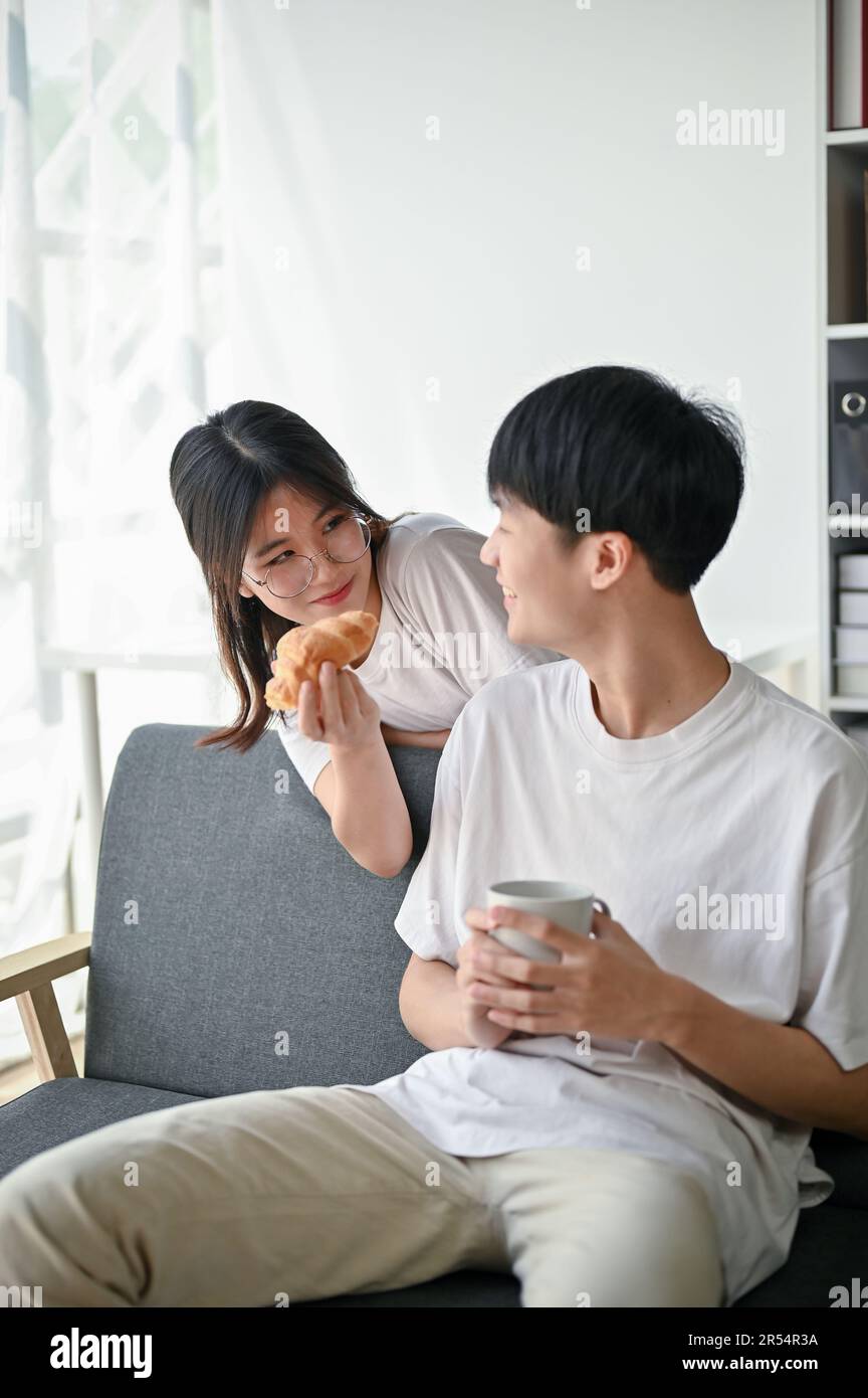 A cute Asian girlfriend playing and feeding a yummy croissant to her ...