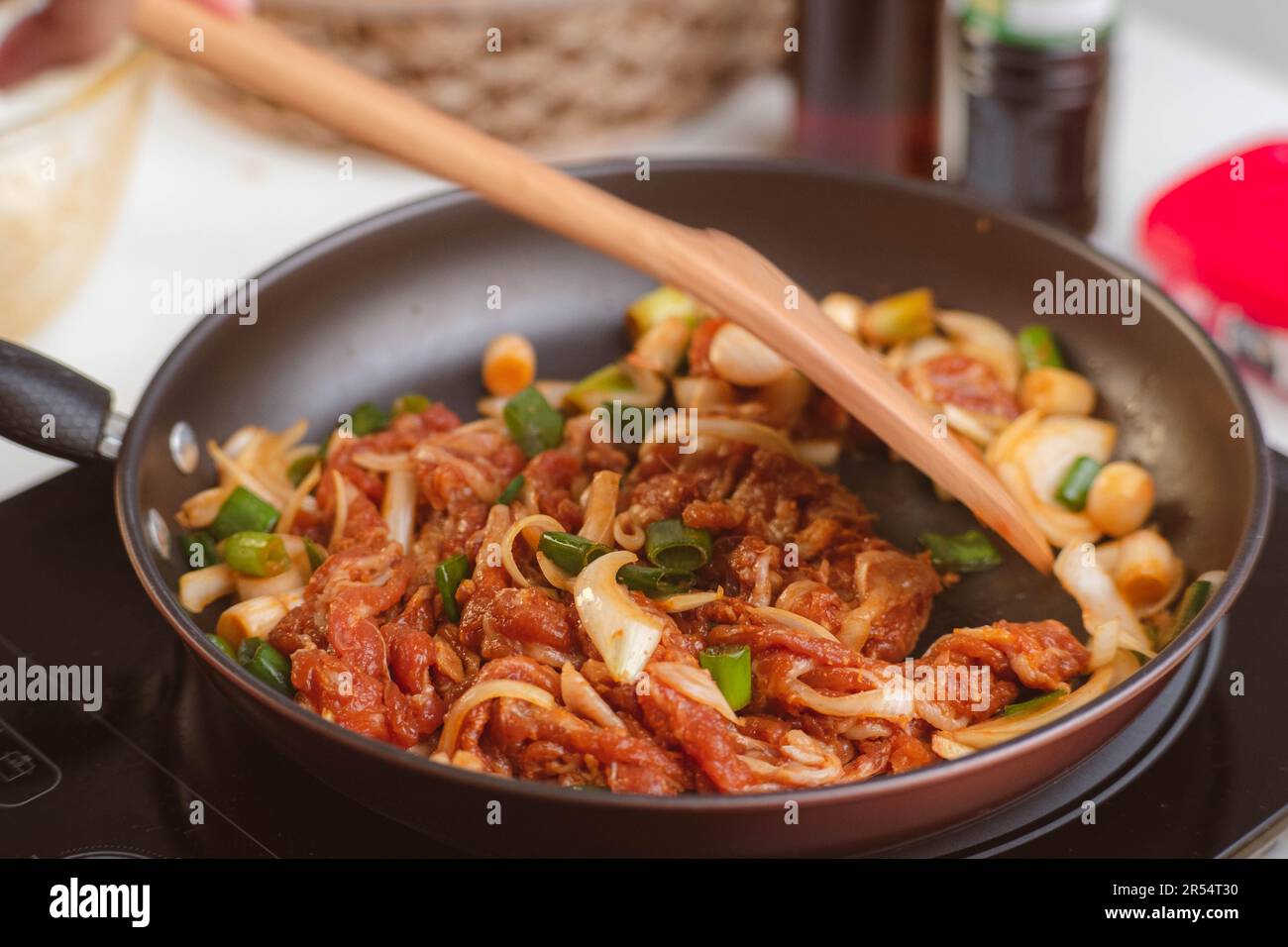 Cooking - Hands holding a ladle stir-frying kimchi and kurobuta pork in ...