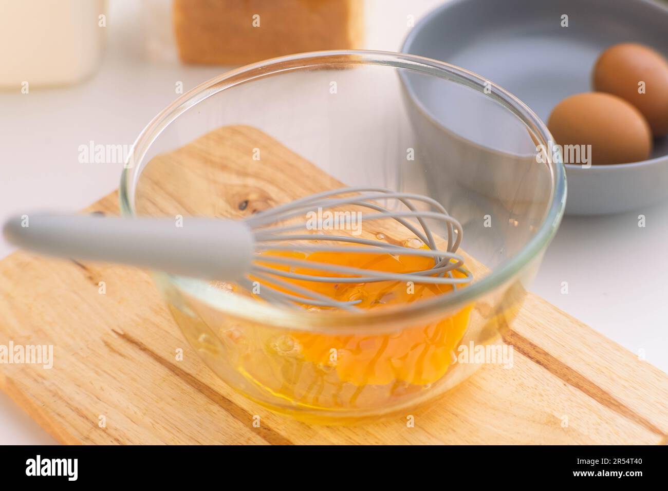 Woman beating eggs in a glass bowl. Young woman cooking in the kitchen ...