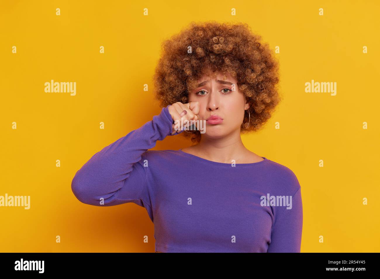 Young sad lady with afro hairstyle in purple longsleeve top posing on ...