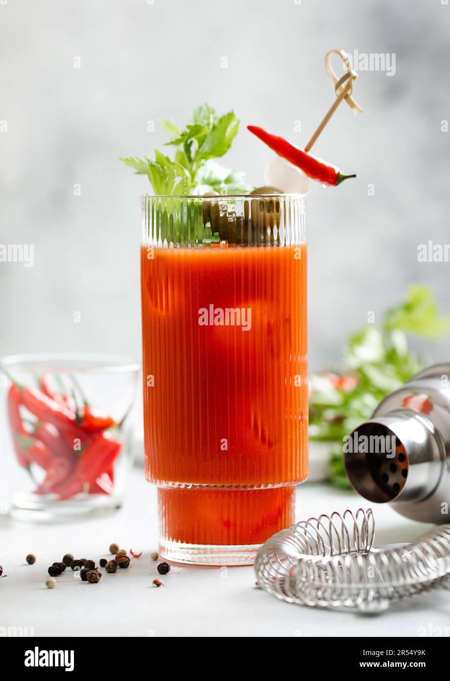 Cocktail bloody mary with shaker and strainer on light kitchen board ...
