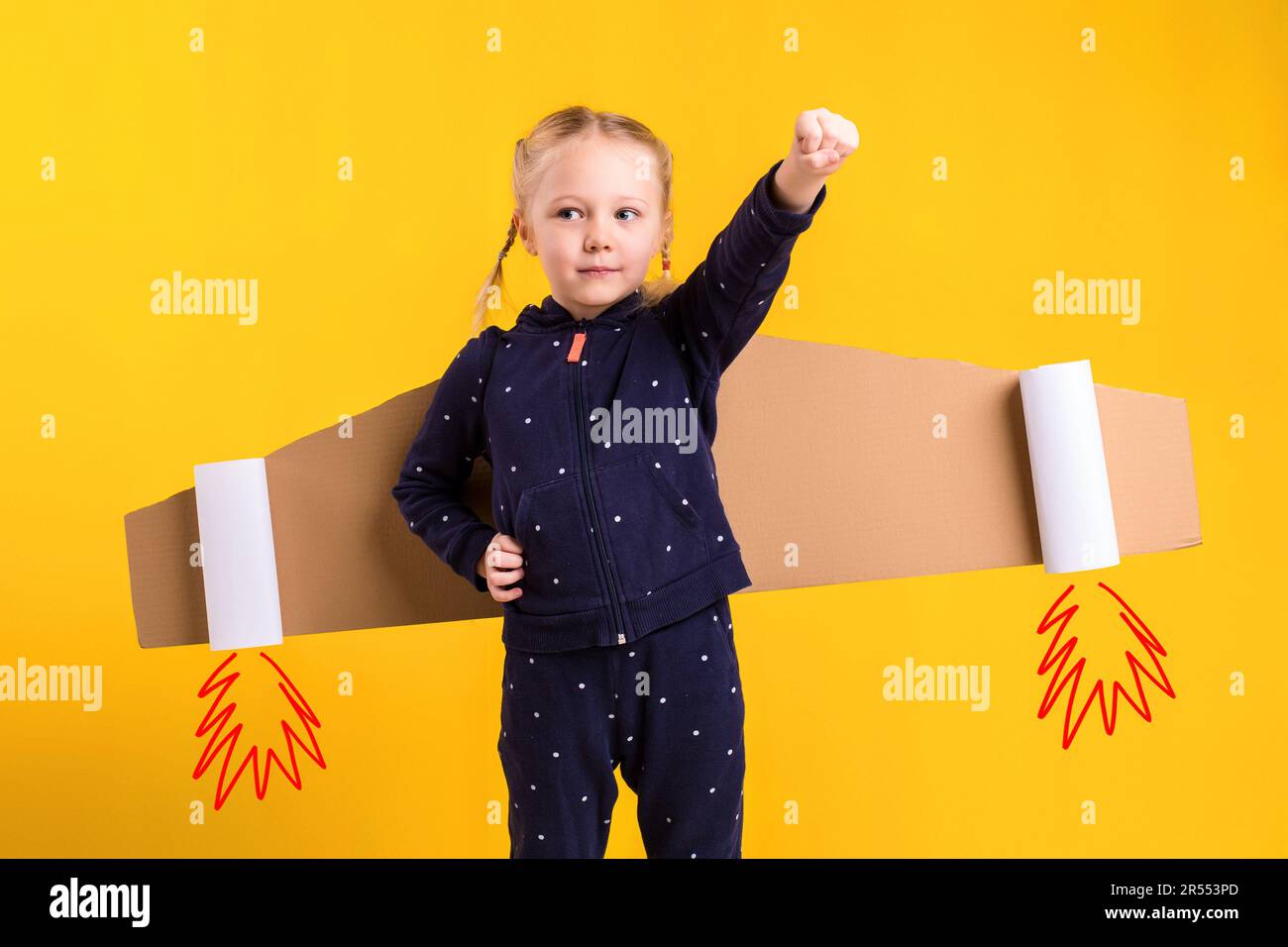 A little child girl is wearing homemade cardboard flying wings ...
