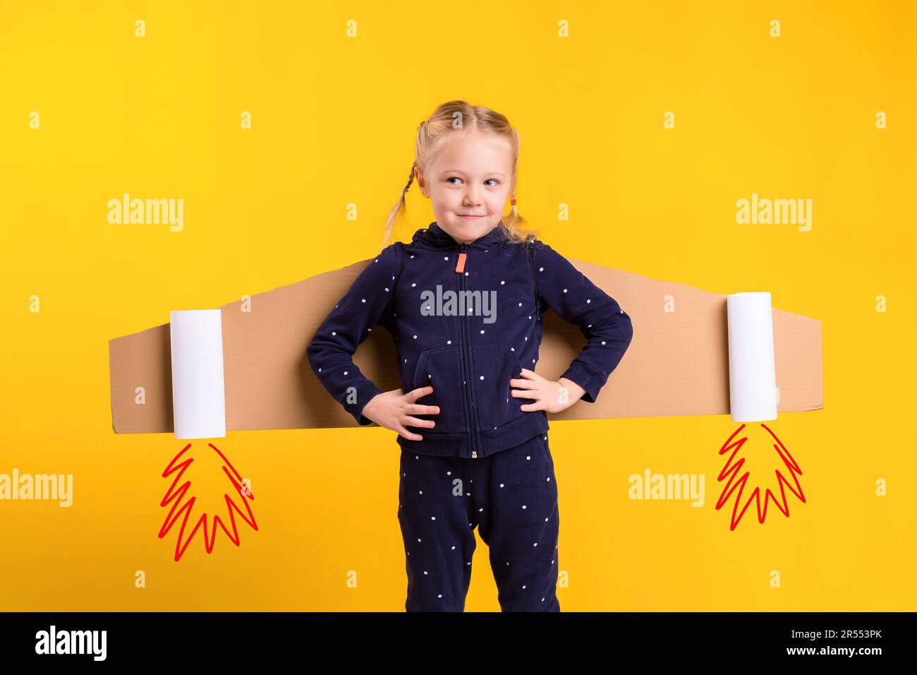 A little child girl is wearing homemade cardboard flying wings ...