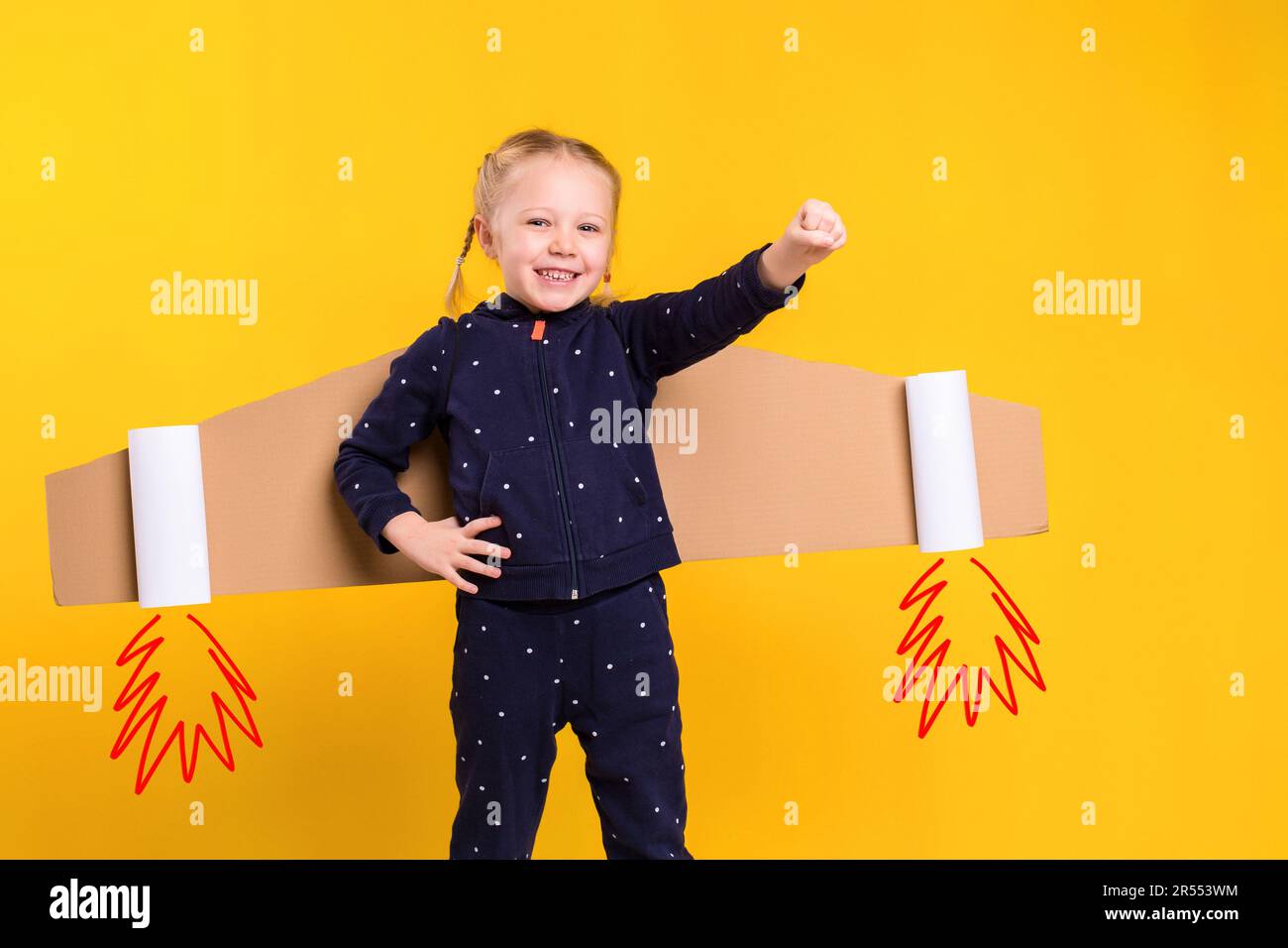 A little child girl is wearing homemade cardboard flying wings ...