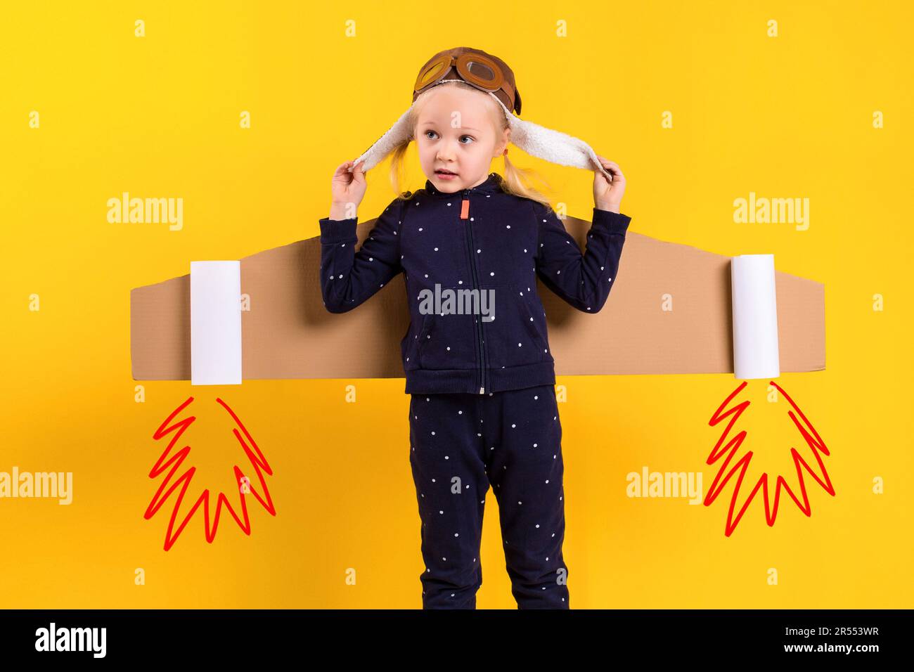 A little child girl is wearing homemade cardboard flying wings ...