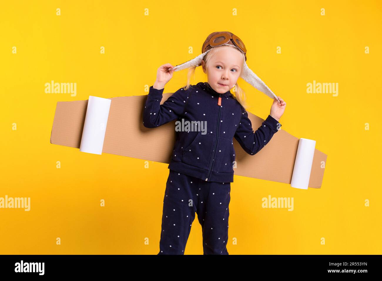 A little child girl is wearing homemade cardboard flying wings ...