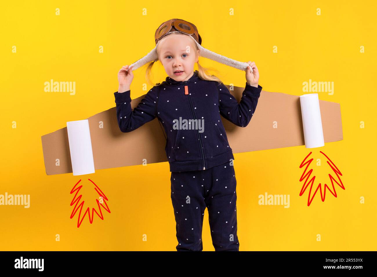 A little child girl is wearing homemade cardboard flying wings ...