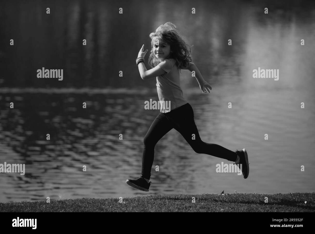 Kids running or jogging near lake on grass in park. Sporty child boy ...
