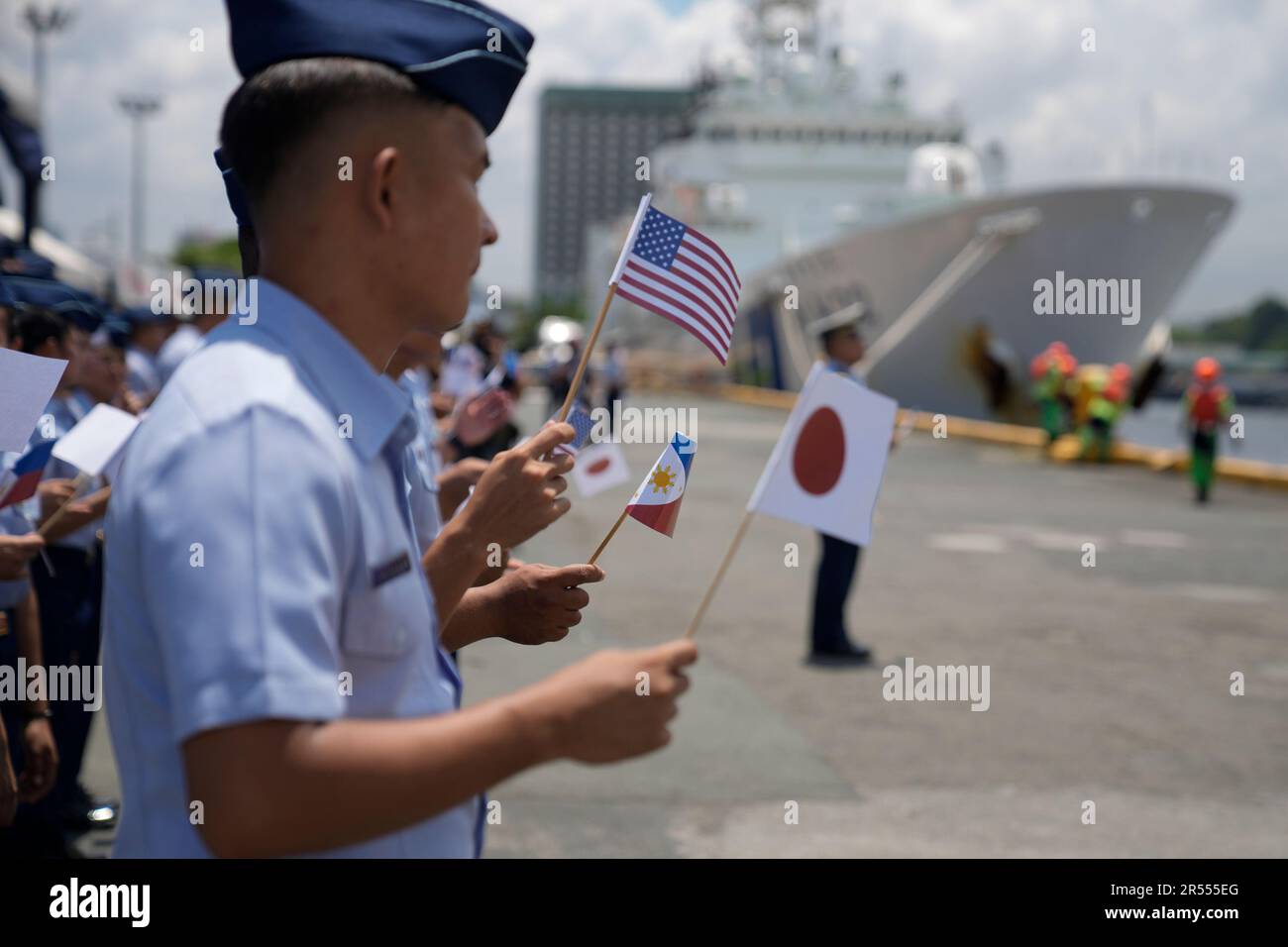 Philippine Coast Guard members wave small flags of the Philippines, U.S ...