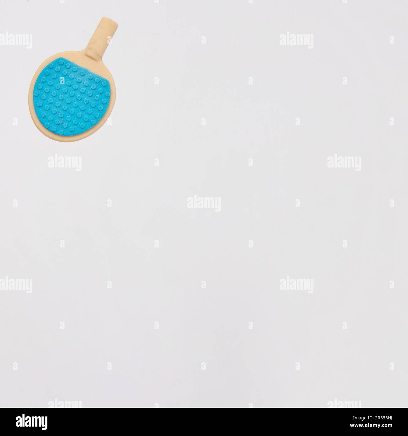 A blue table tennis racket in the upper left on a white background with ...