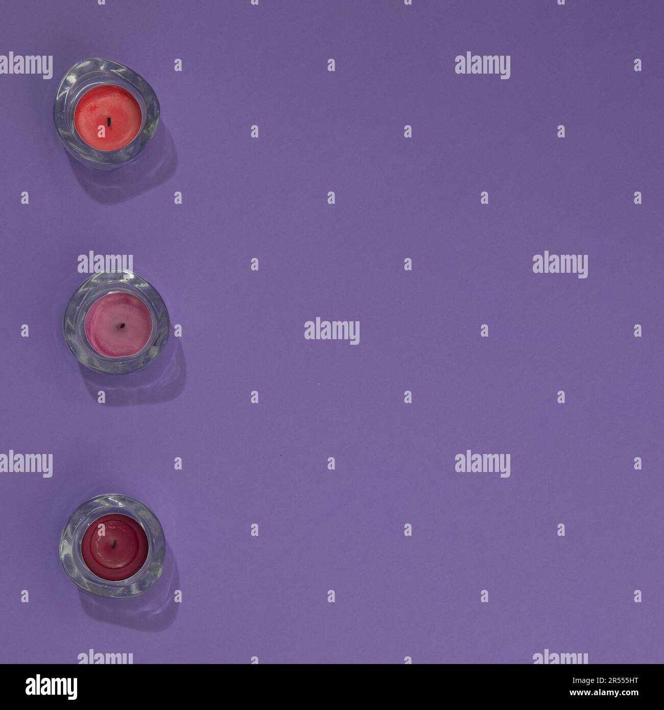 Three glass candlesticks with colored candles lined up vertically on ...