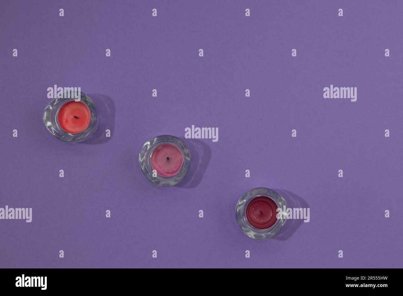 Three glass candlesticks with colored candles arranged in a line on a ...